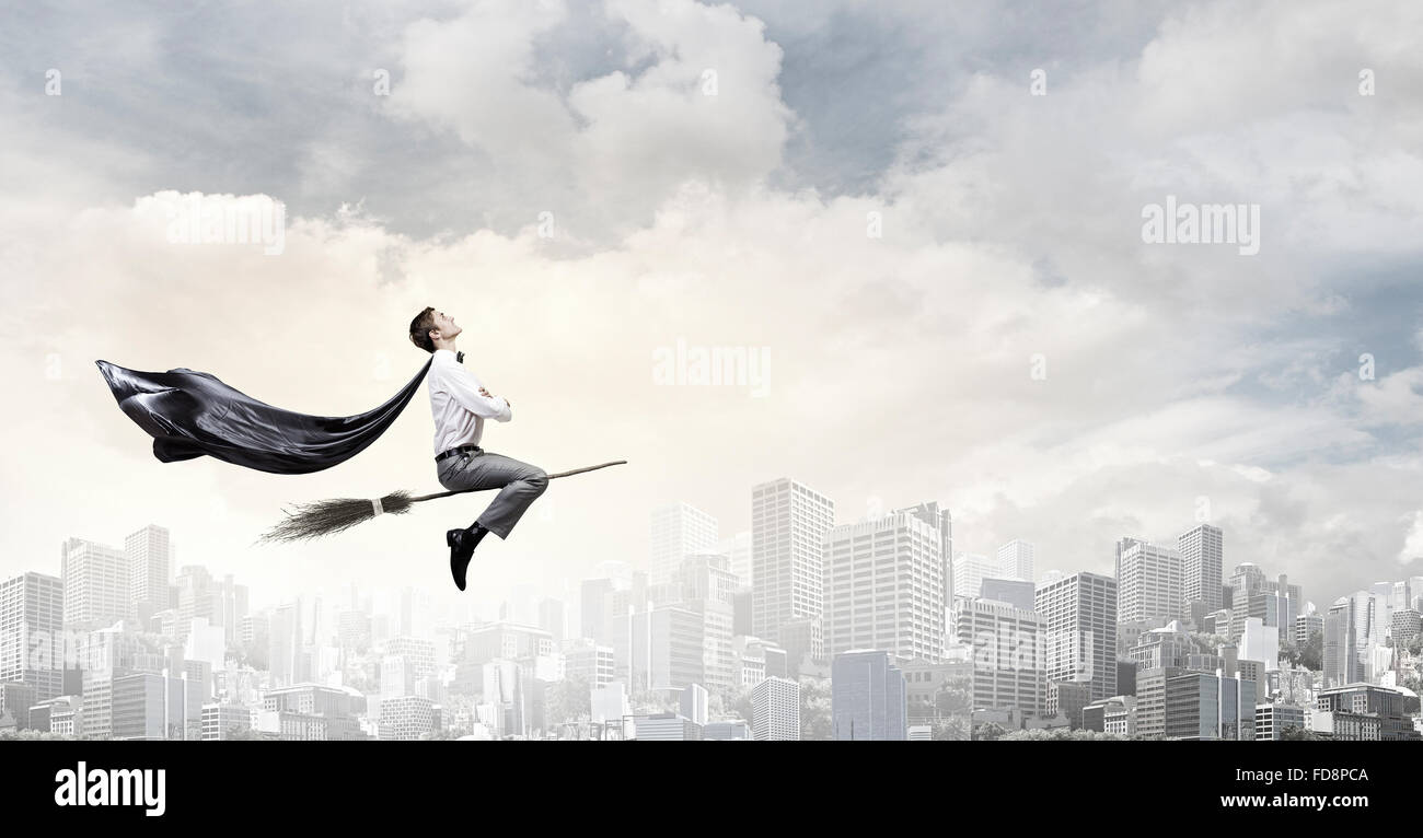 Young businessman flying on broom high in sky Stock Photo - Alamy