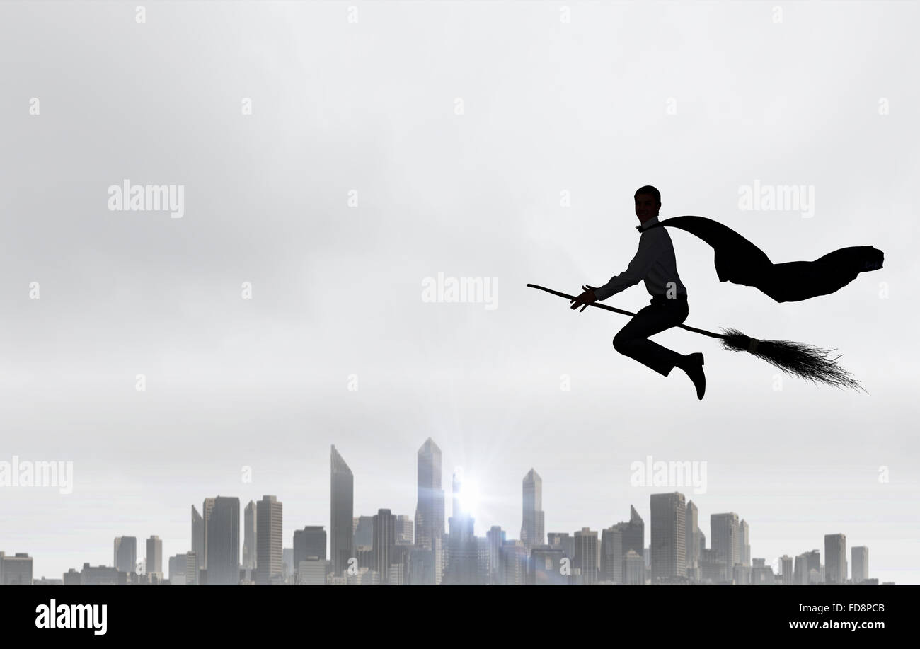 Young businessman flying on broom high in sky Stock Photo - Alamy