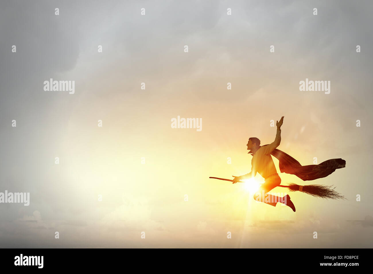 Young businessman flying on broom high in sky Stock Photo - Alamy