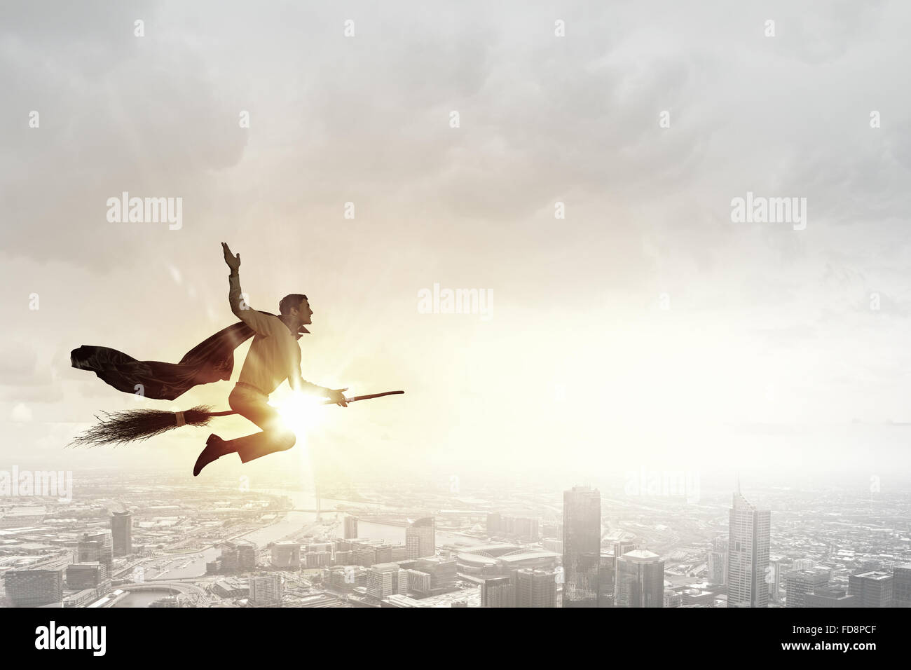 Young businessman flying on broom high in sky Stock Photo - Alamy