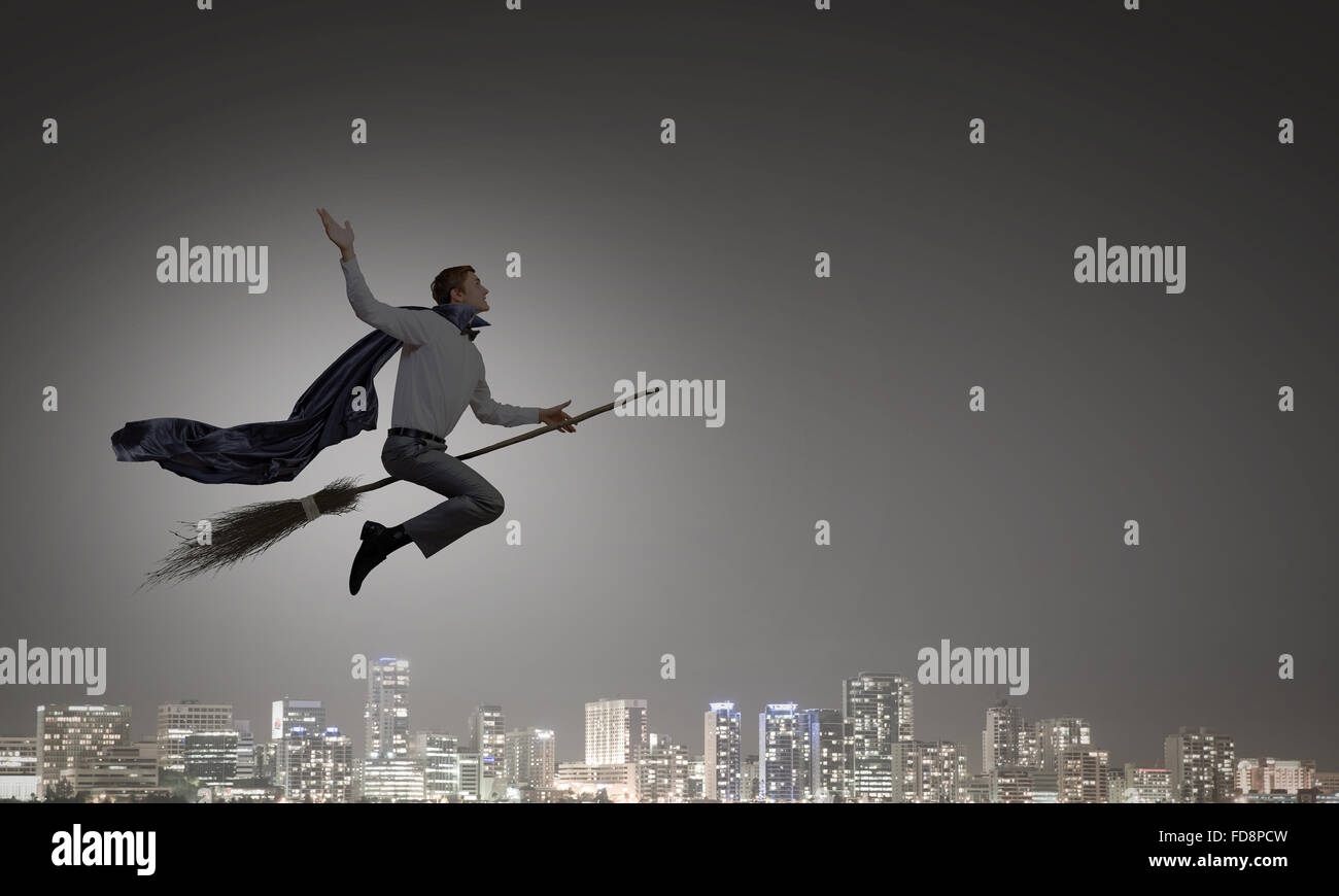 Young businessman flying on broom high in sky Stock Photo - Alamy
