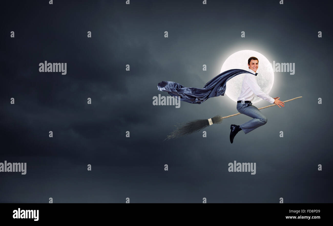 Young businessman flying on broom high in sky Stock Photo - Alamy