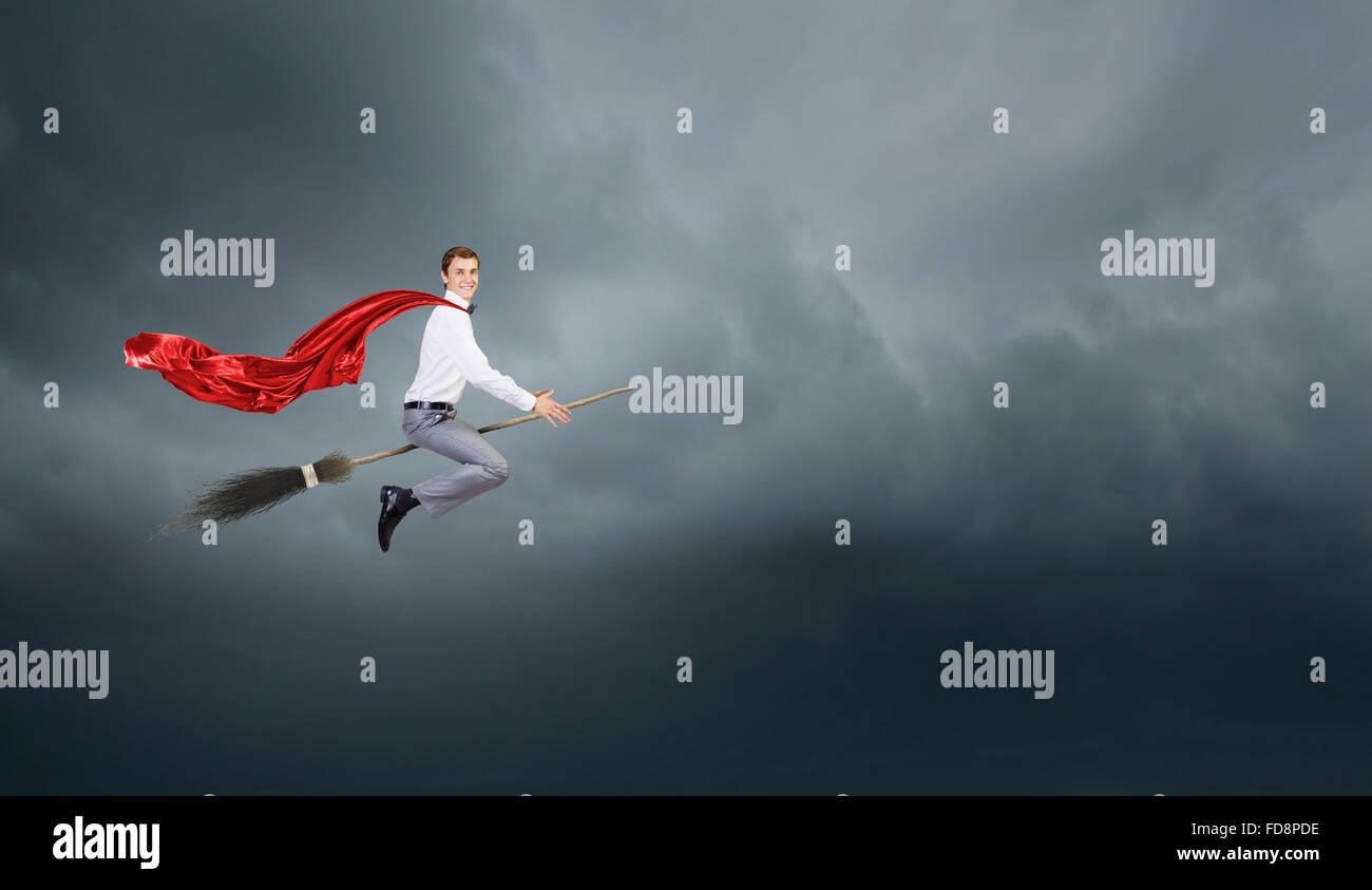 Young businessman flying on broom high in sky Stock Photo - Alamy