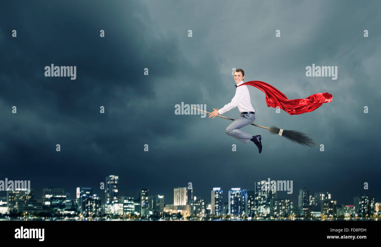 Young businessman flying on broom high in sky Stock Photo - Alamy