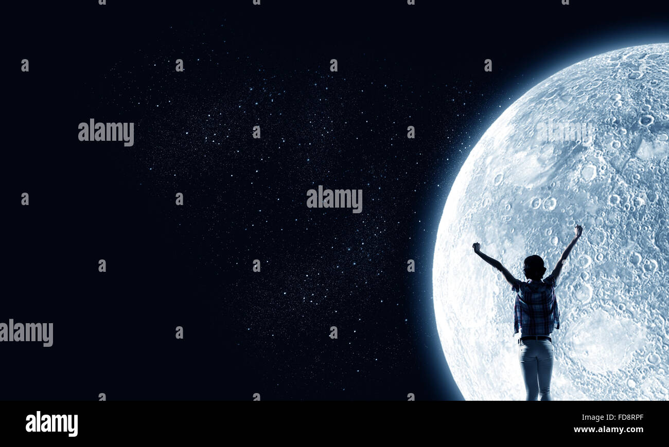 Rear view of young woman with hands up looking at moon in sky Stock ...