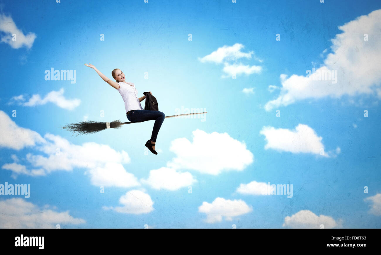 Young girl in casual flying on broom high in sky Stock Photo - Alamy