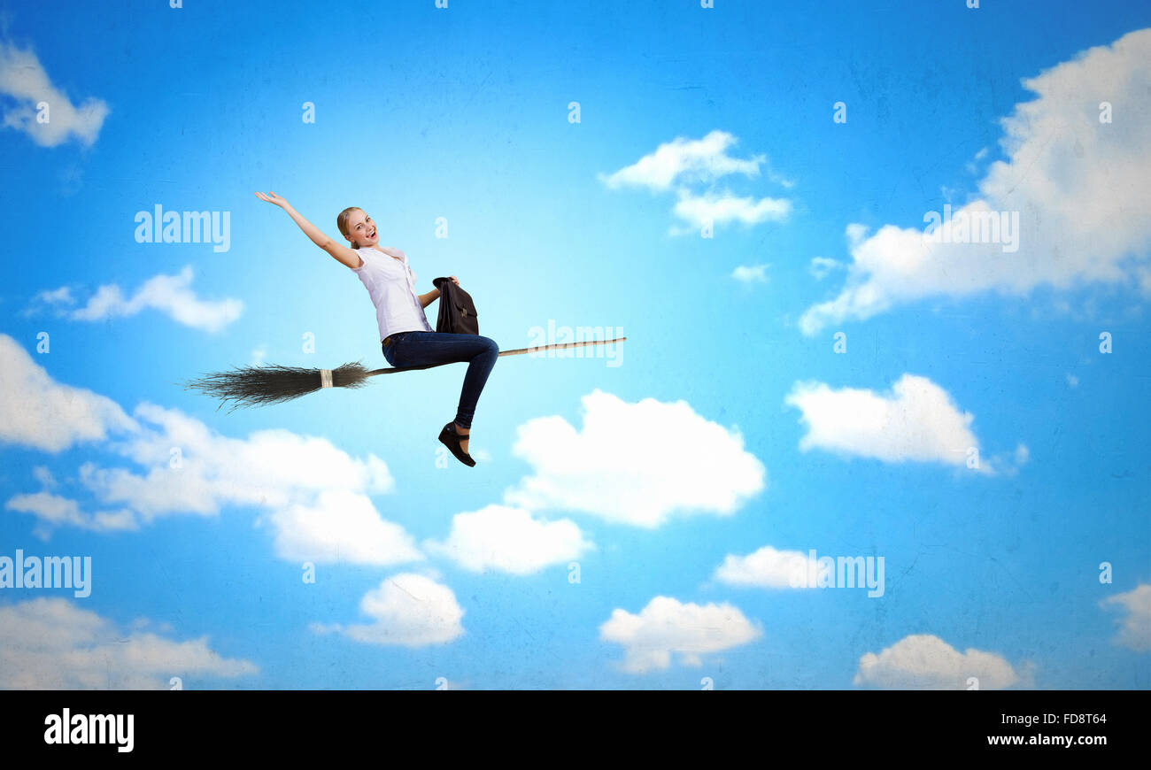 Young girl in casual flying on broom high in sky Stock Photo - Alamy