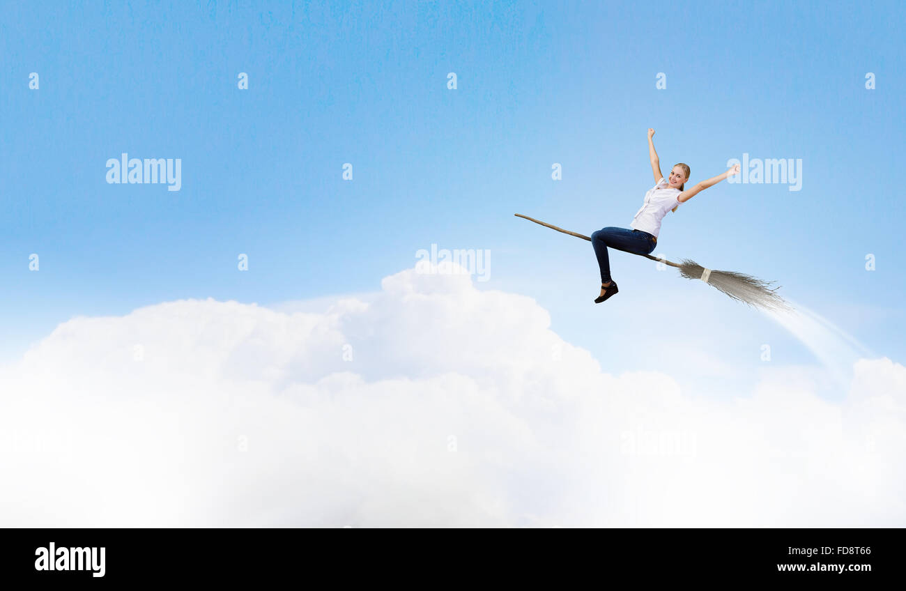 Young girl in casual flying on broom high in sky Stock Photo - Alamy