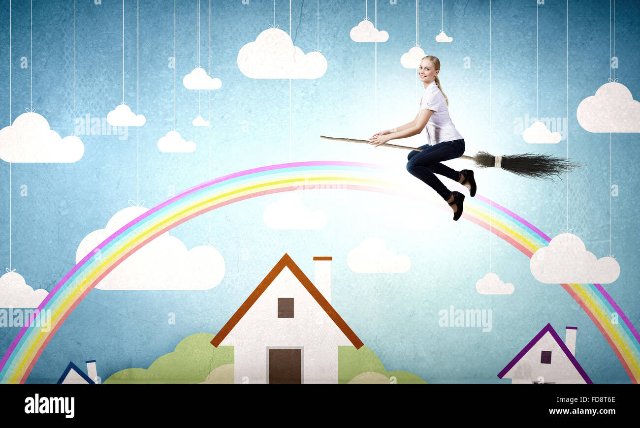 Young girl in casual flying on broom high in sky Stock Photo - Alamy