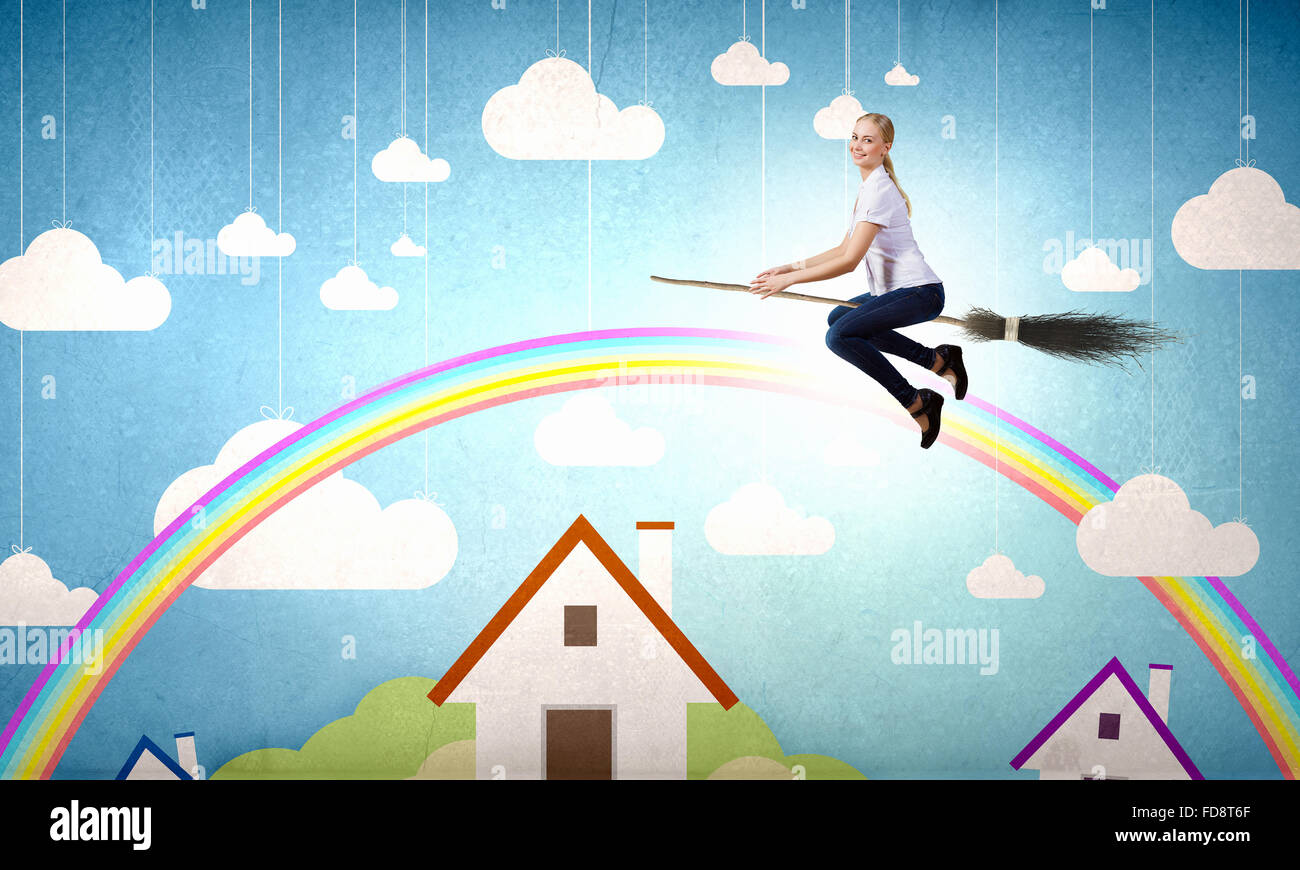 Young girl in casual flying on broom high in sky Stock Photo - Alamy
