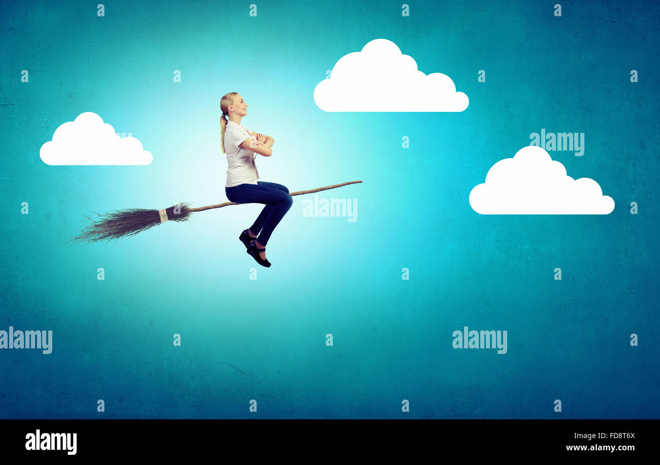 Young girl in casual flying on broom high in sky Stock Photo - Alamy