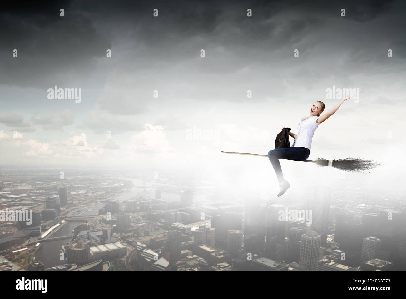 Young girl in casual flying on broom high in sky Stock Photo - Alamy