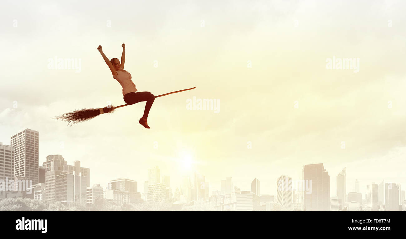 Young girl in casual flying on broom high in sky Stock Photo - Alamy
