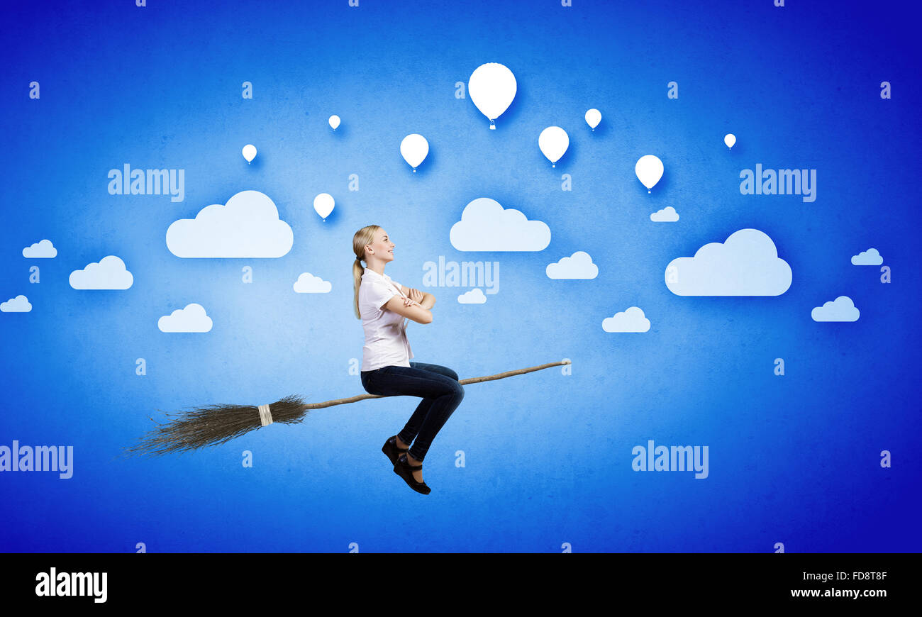 Young girl in casual flying on broom high in sky Stock Photo - Alamy