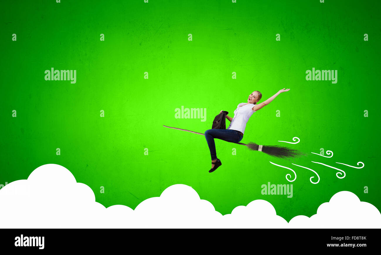 Young girl in casual flying on broom high in sky Stock Photo - Alamy