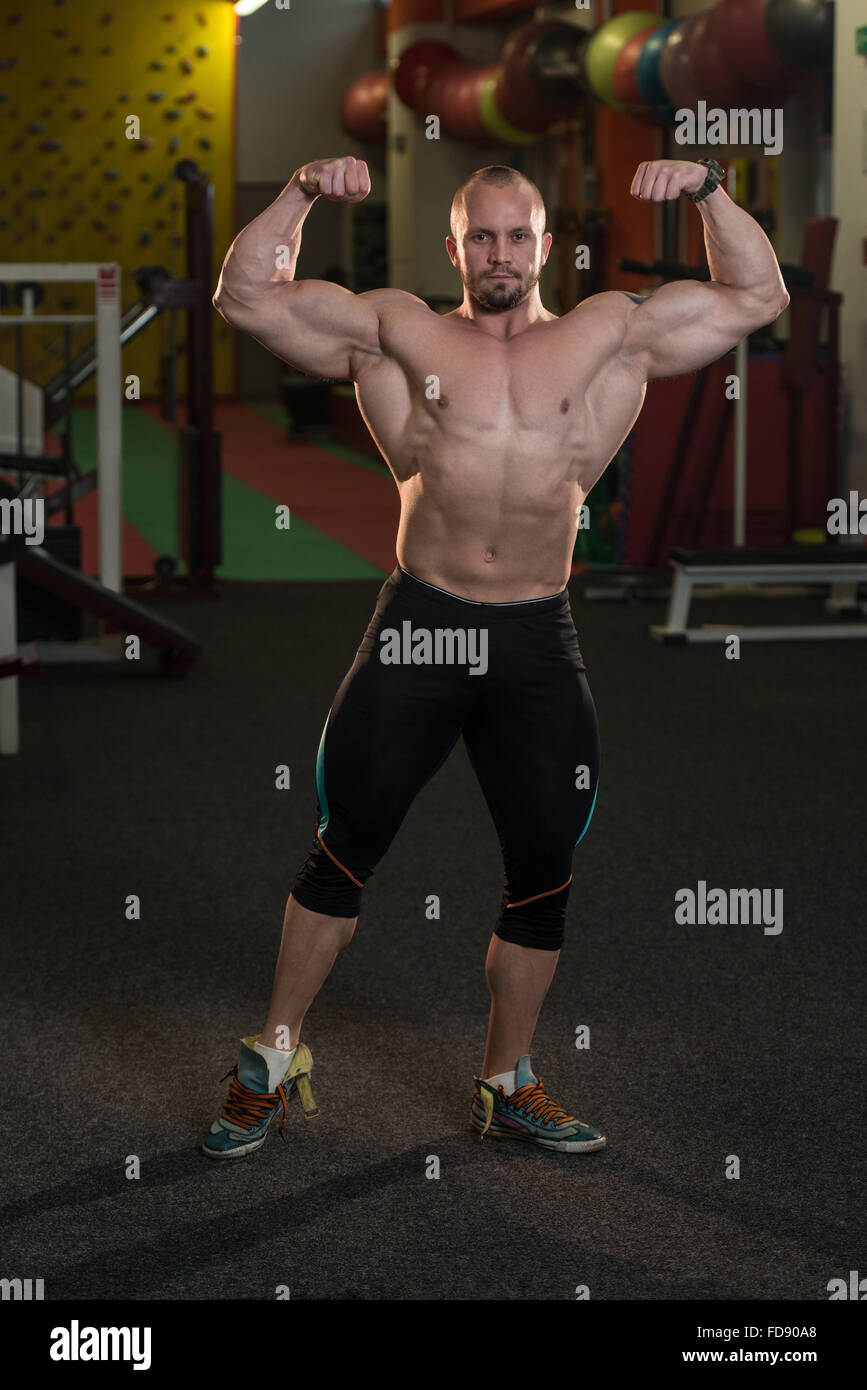 Serious Man Standing Strong In The Gym And Flexing Muscles Stock Photo ...