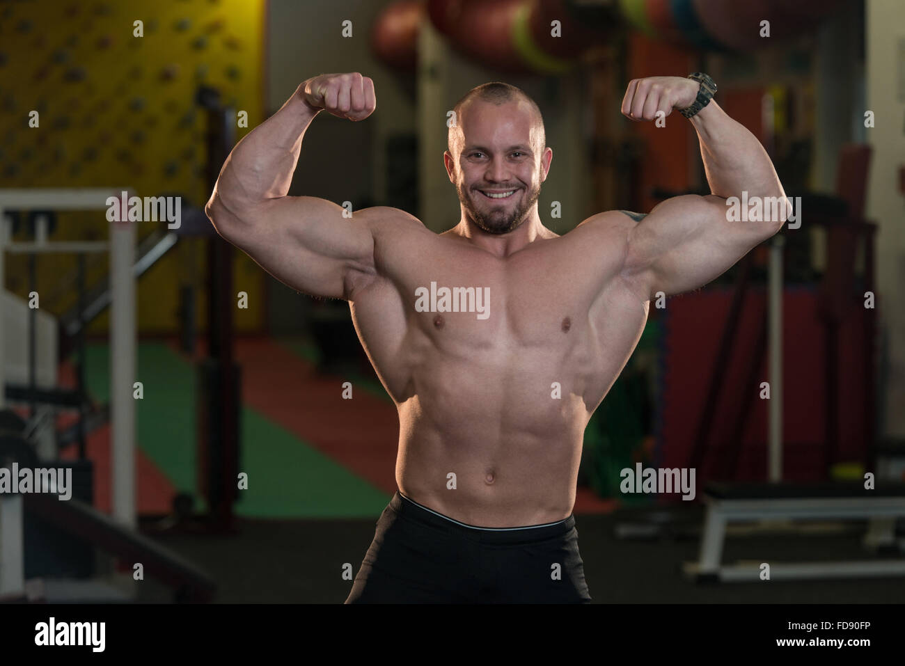 Serious Man Standing Strong In The Gym And Flexing Muscles Stock Photo ...