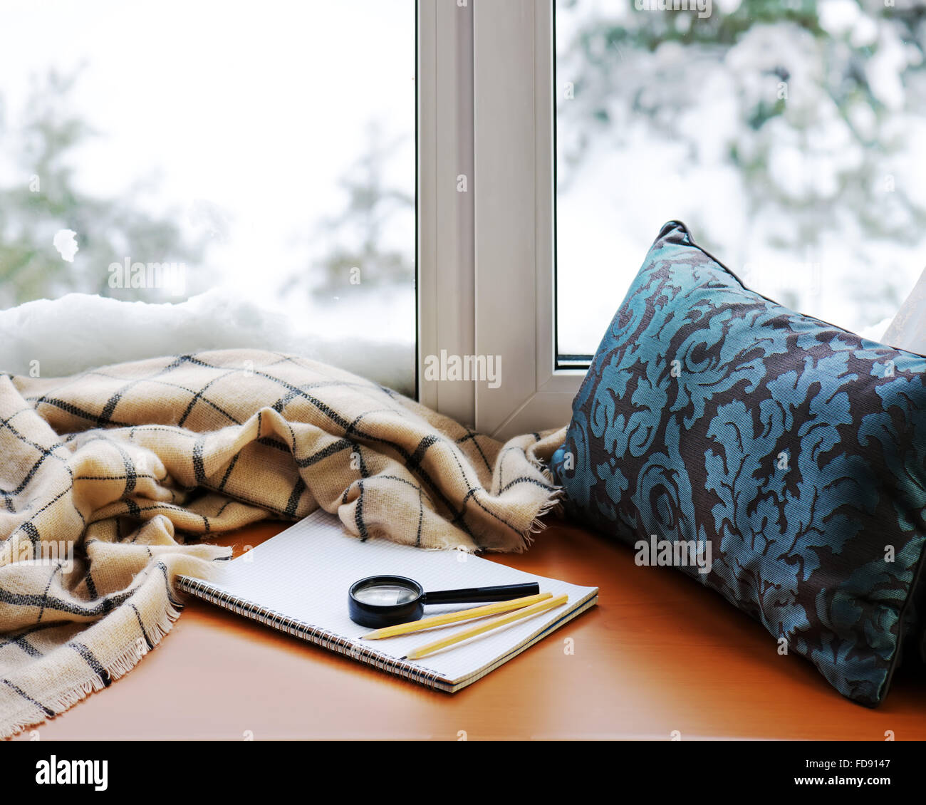 Open notepad, magnifier glass, pillow, pencils and beige warm plaid ...