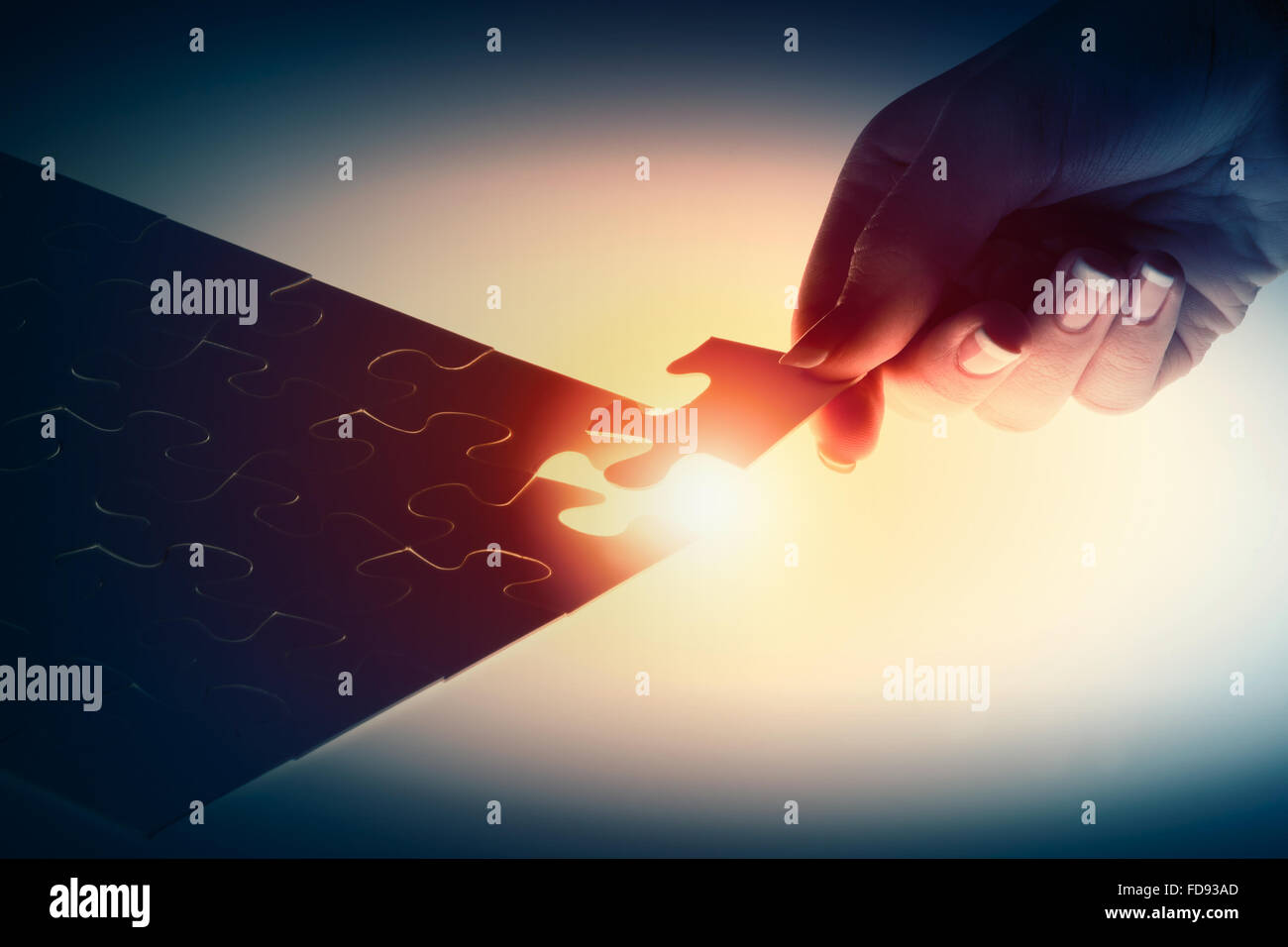 Close up of hands connecting puzzle element and making jigsaw complete ...