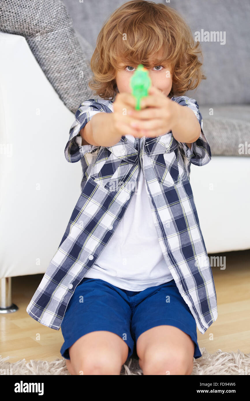 Boy aiming with toy gun at camera t home Stock Photo - Alamy