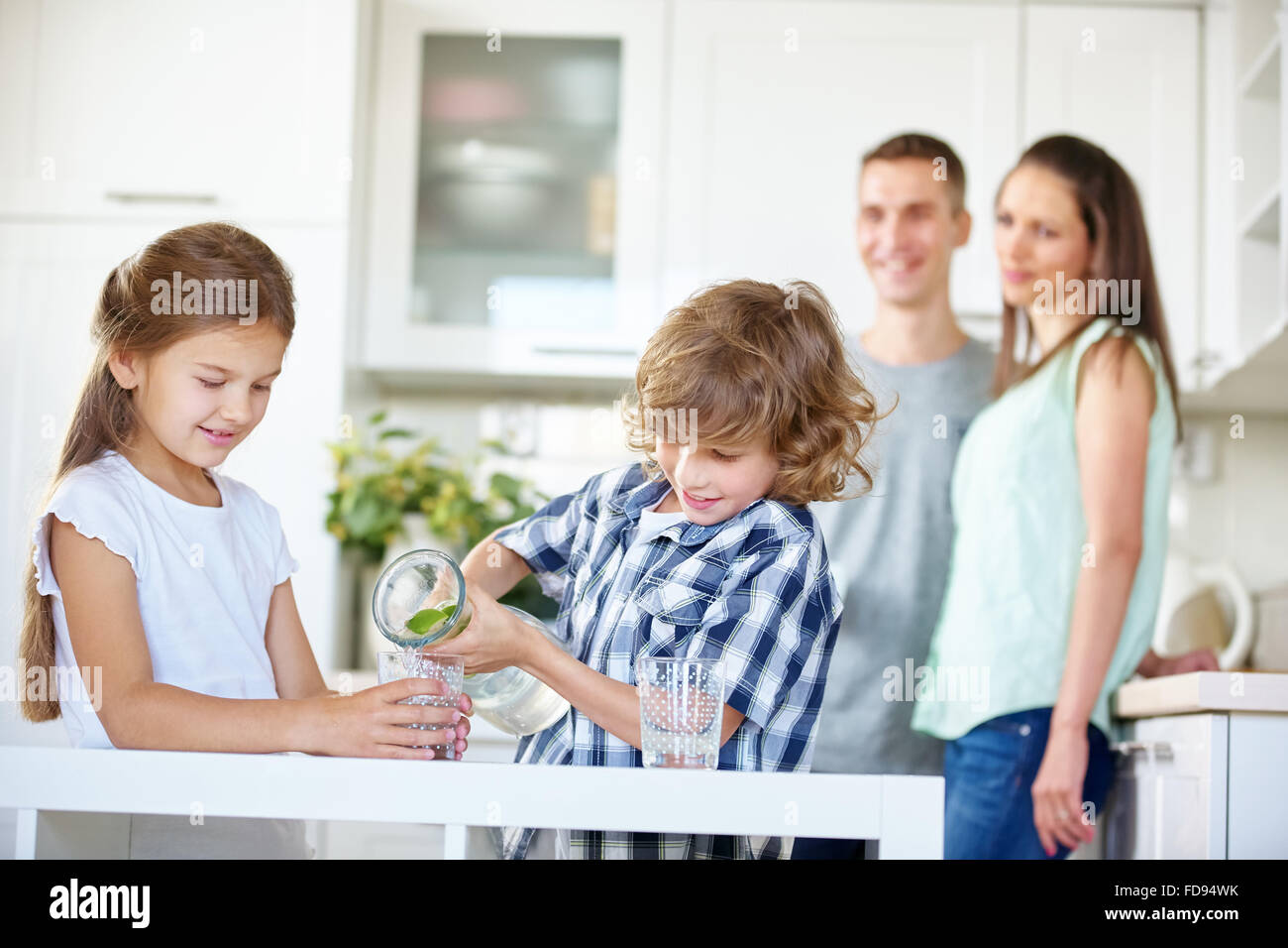 Two children drinking water with fresh lime in the kitchen while ...