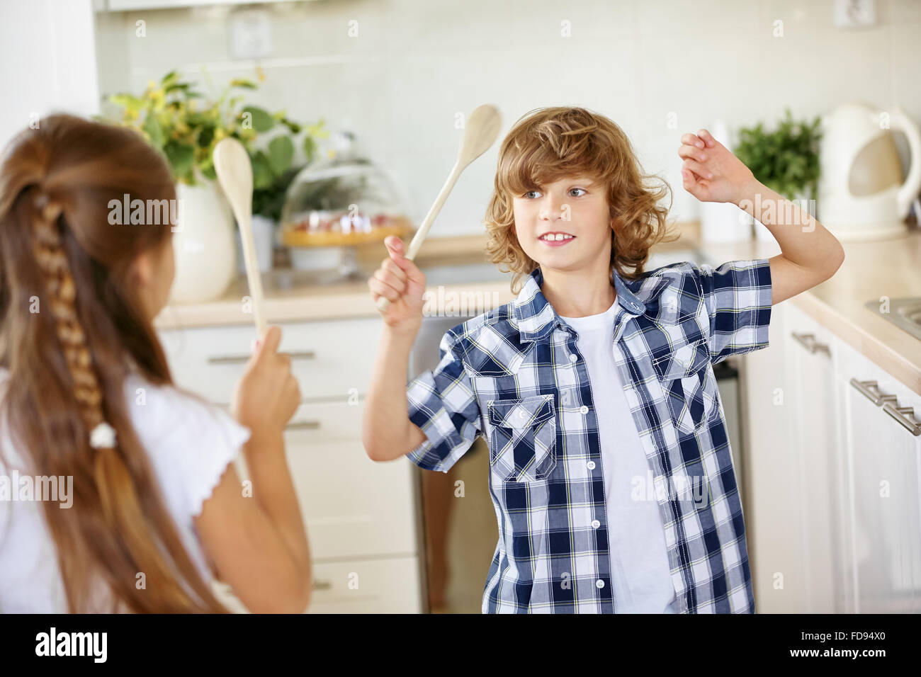 Two children fighting in fun with wooden spoons in the kitchen Stock ...