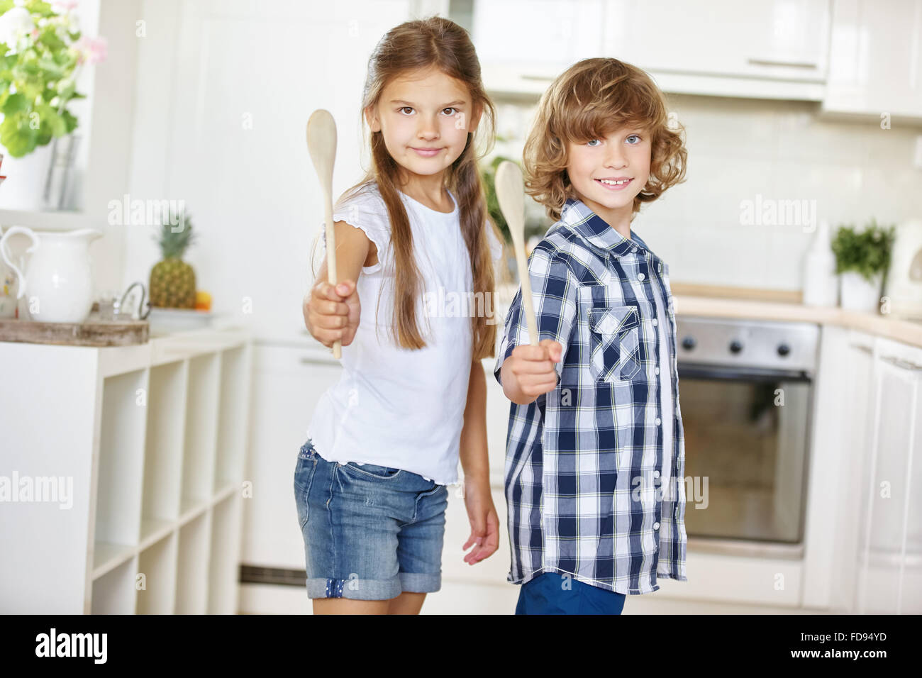 Two children playing with wooden spoons in the kitchen Stock Photo - Alamy