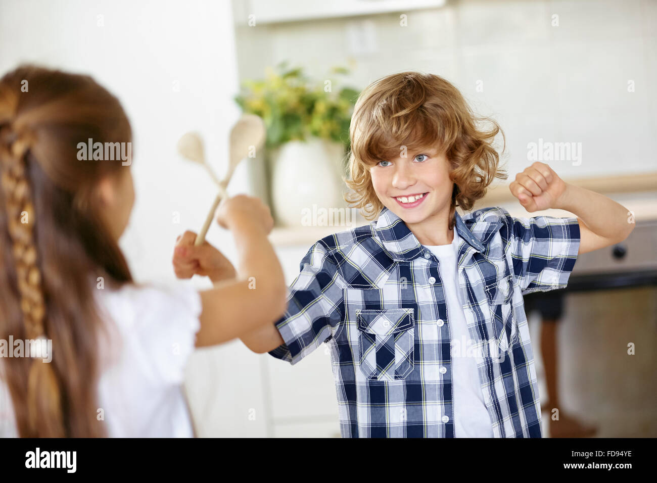 Two children fighting in jest in the kitchen with wooden spoons Stock ...