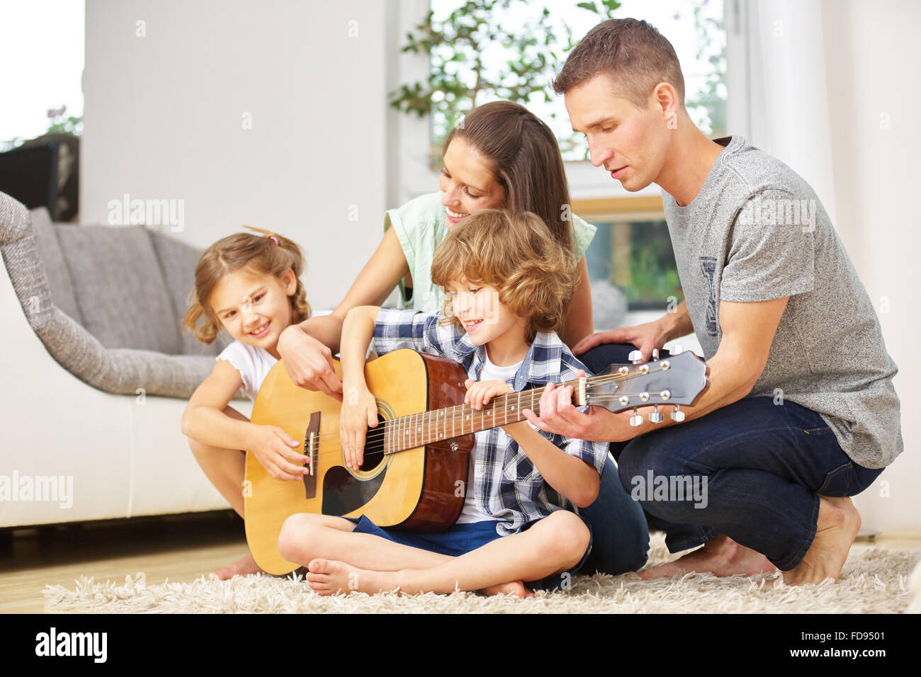 Family making music with guitar at home in the living room Stock Photo ...