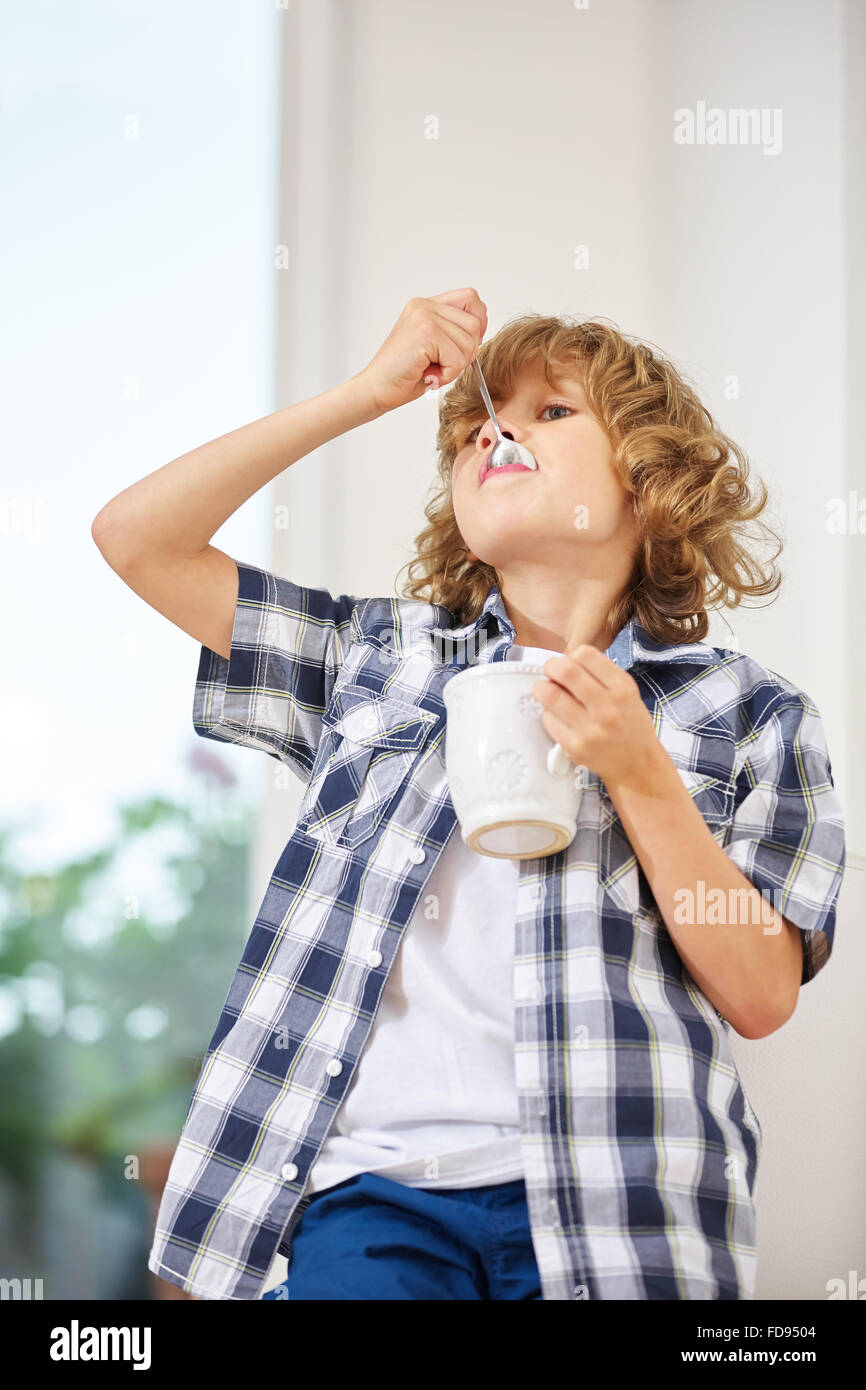 Happy boy with cup of hot chocolate and a spoon at home Stock Photo - Alamy