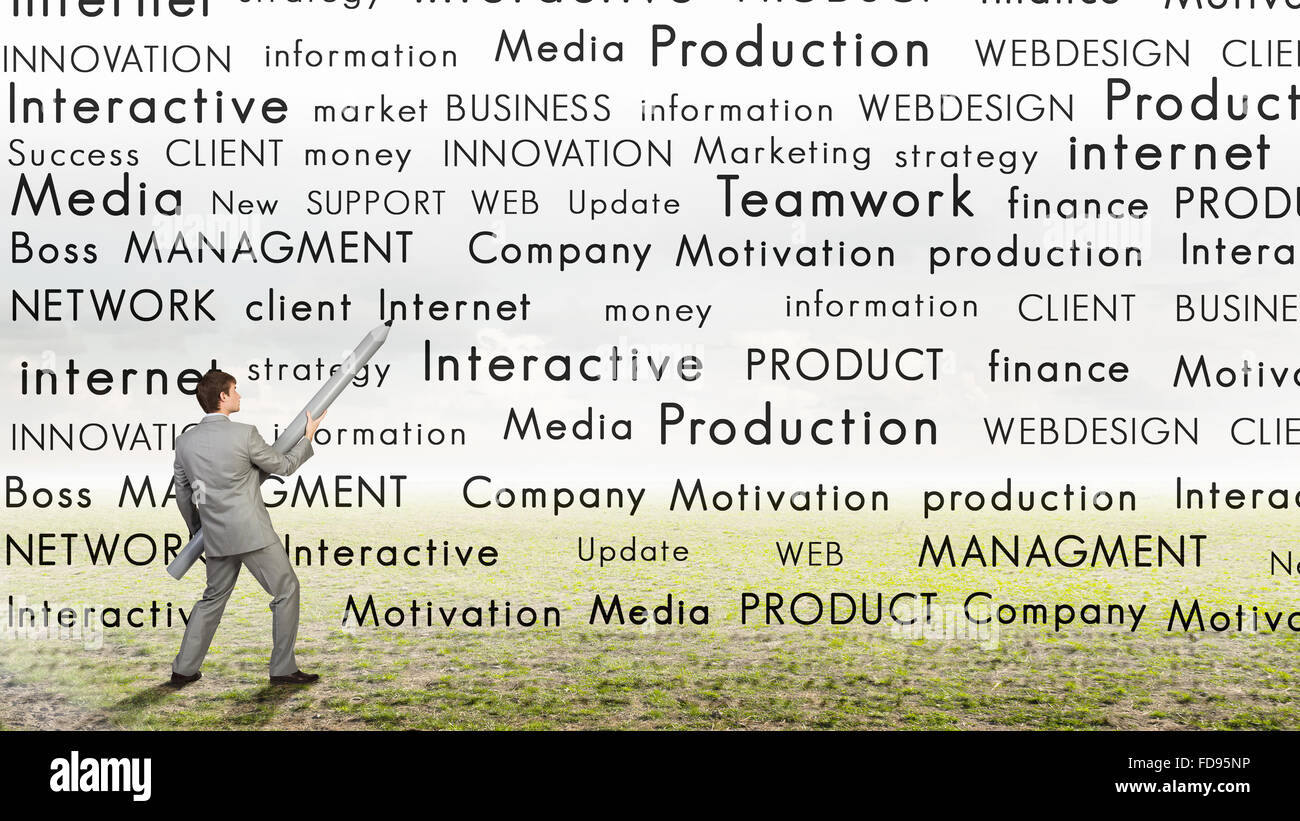 Young businessman writing business words with huge pencil Stock Photo ...