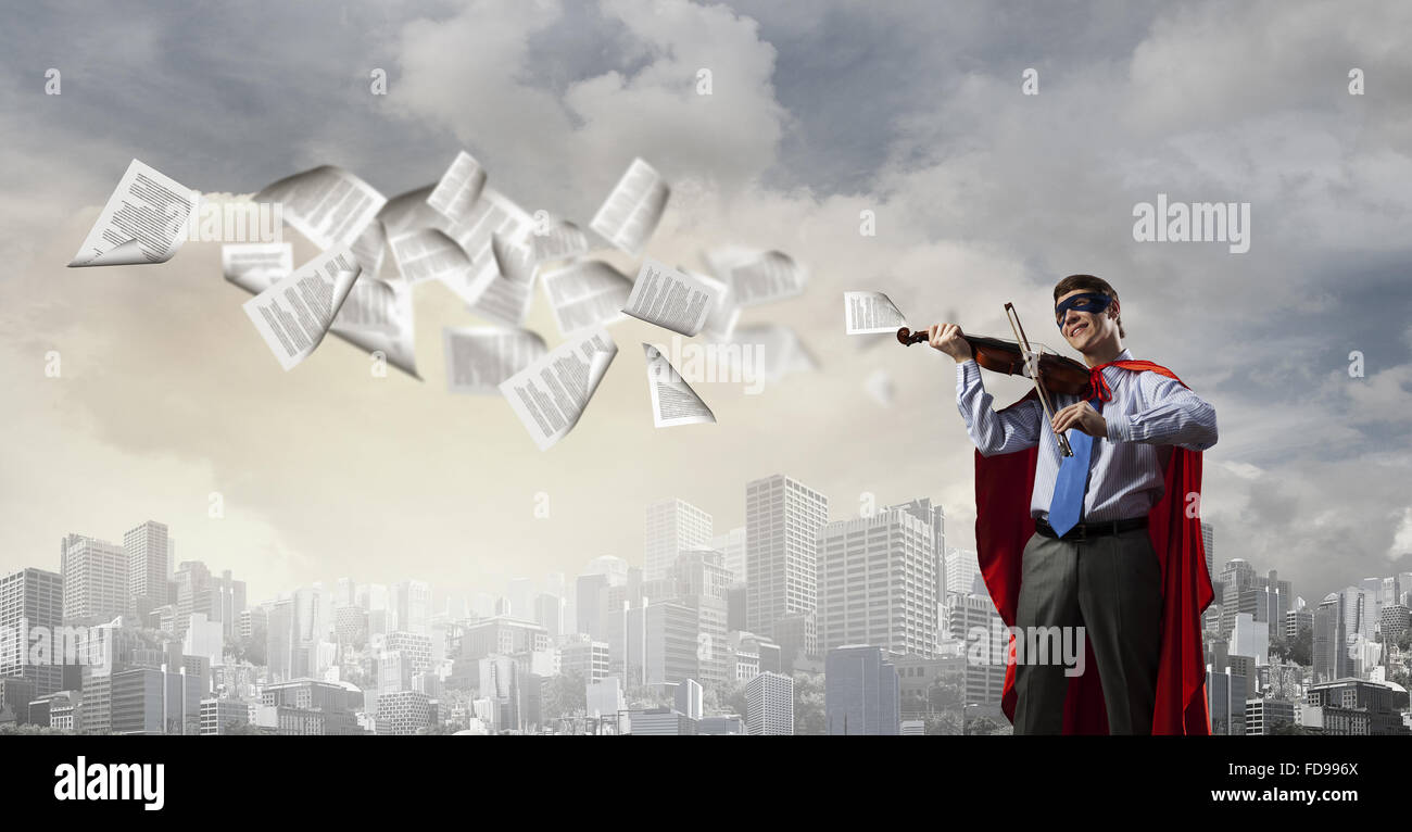 Young man in superhero costume playing violin Stock Photo - Alamy