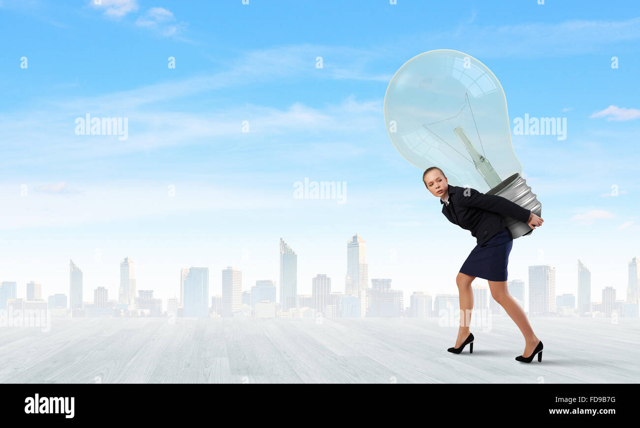 Young businesswoman carrying big light bulb on back Stock Photo - Alamy