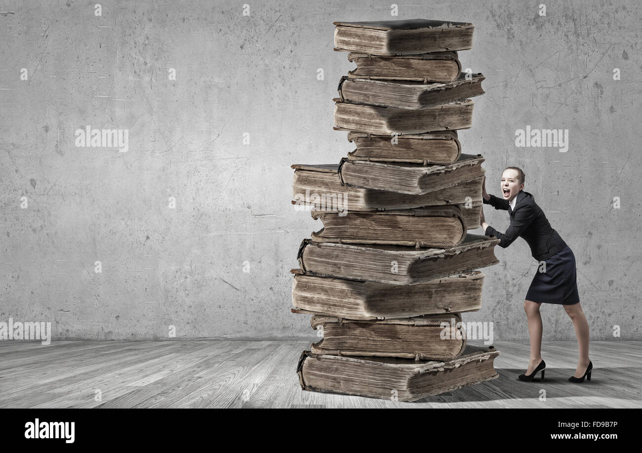 Young woman pushing huge pile of old books Stock Photo - Alamy