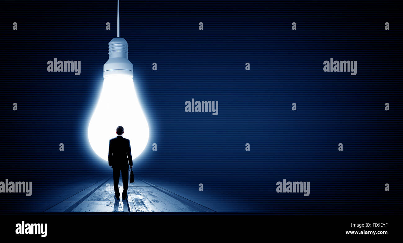 Rear view of businessman with suitcase looking at light bulb Stock ...