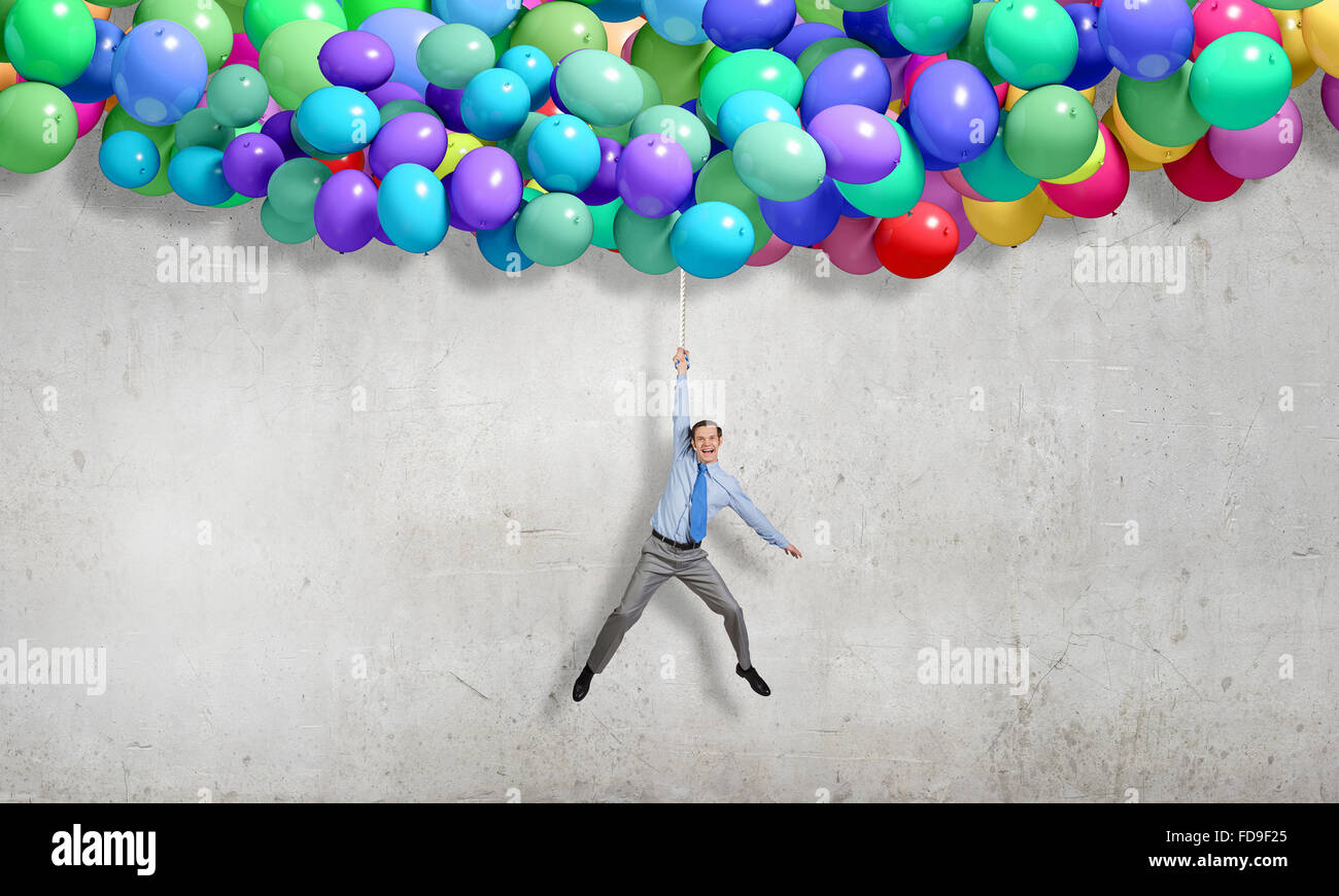 Young successful businessman flies on bunch of colorful balloons Stock ...