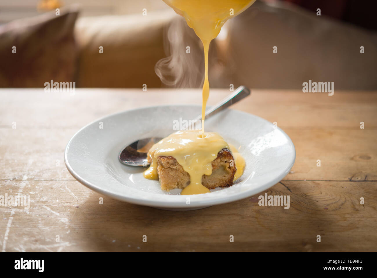 A steamed sponge pudding and custard desert on a wooden table Stock ...