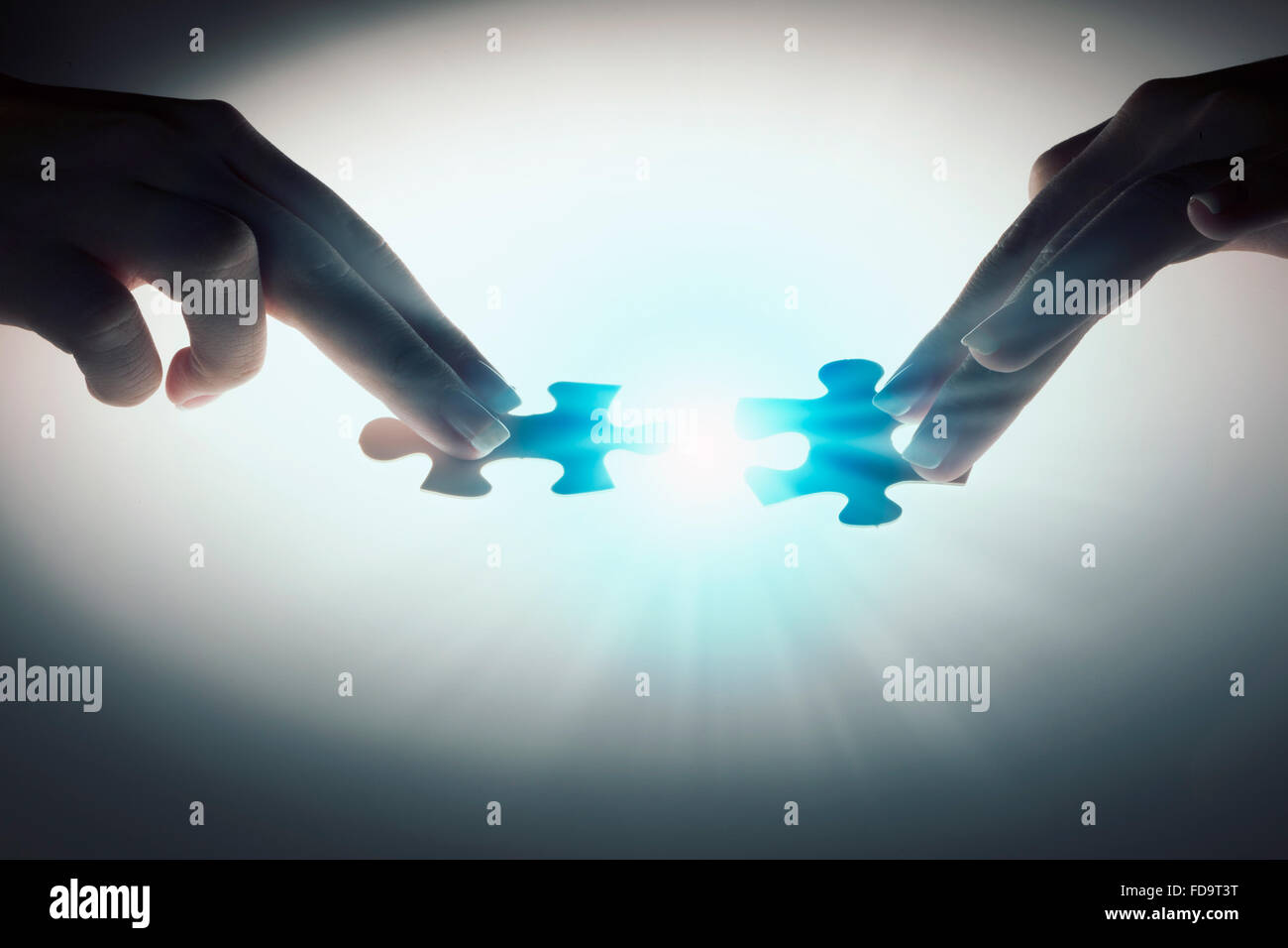Hand connecting two jigsaw glowing puzzle pieces Stock Photo - Alamy