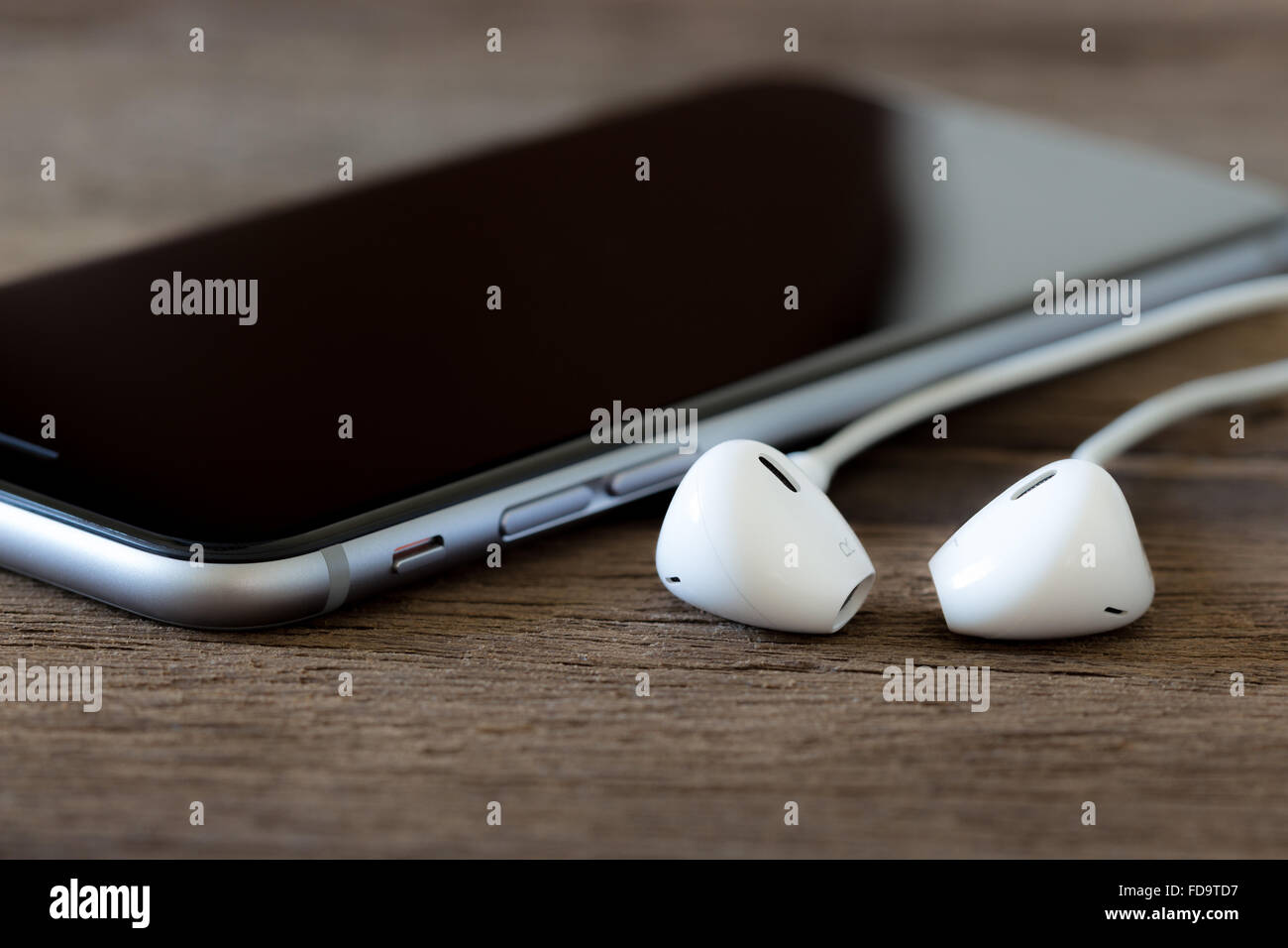 closeup phone and earbuds on wood desk Stock Photo - Alamy