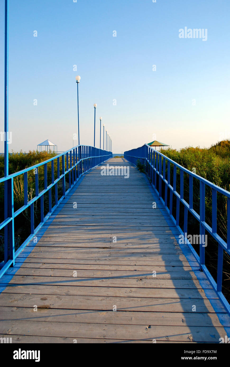 Dock path to the sea with colorful blue handhelds Stock Photo - Alamy
