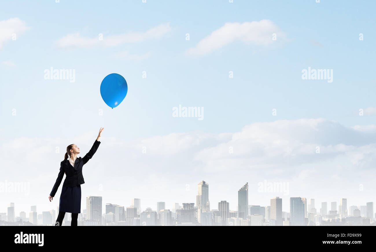 Young businesswoman reaching hand to touch balloon in sky Stock Photo ...