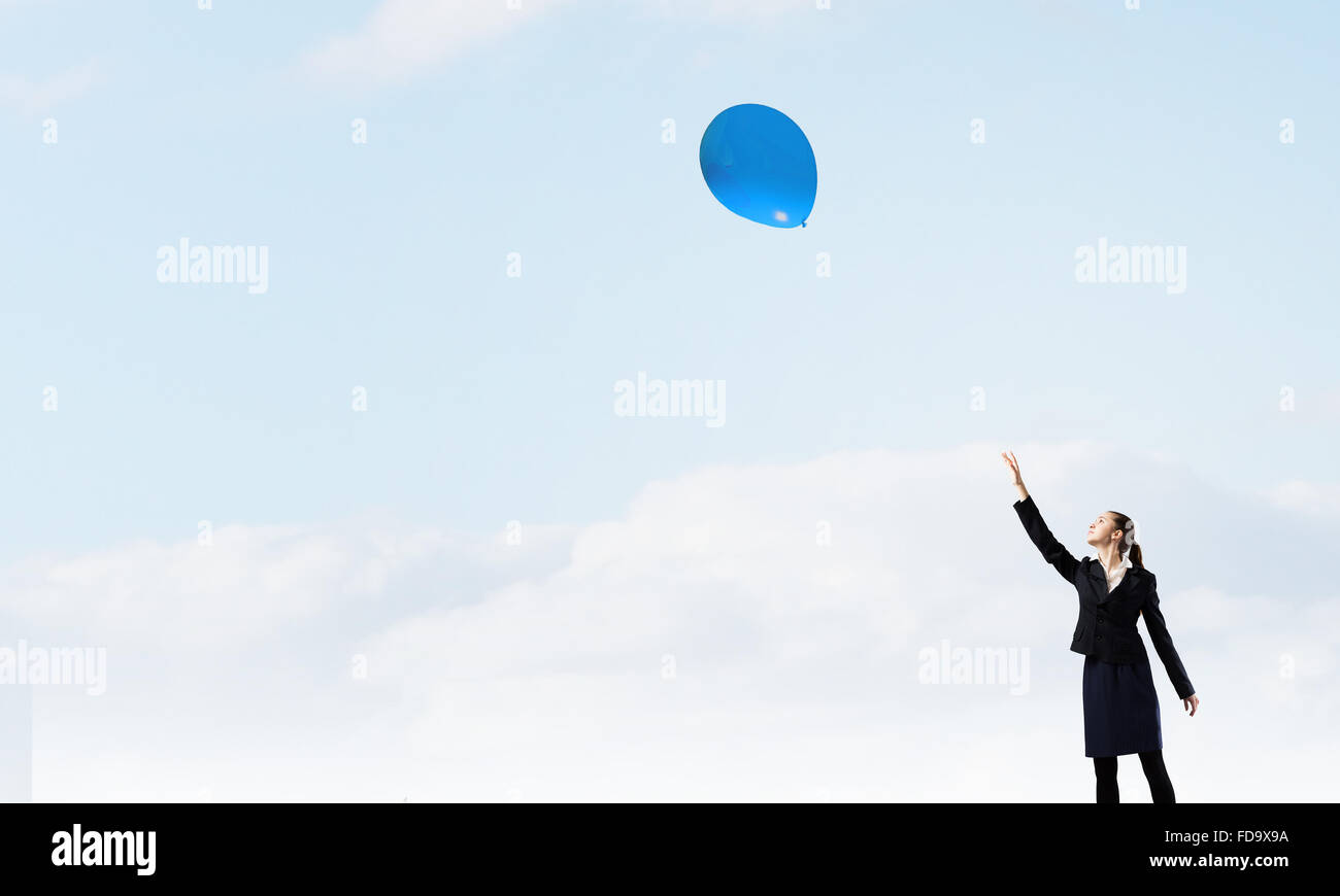 Young businesswoman reaching hand to touch balloon in sky Stock Photo ...