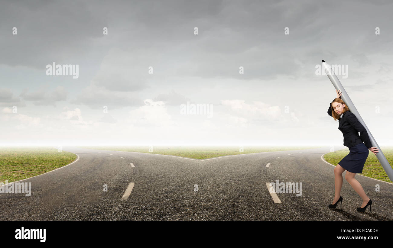 Young businesswoman carrying big pencil on back Stock Photo - Alamy