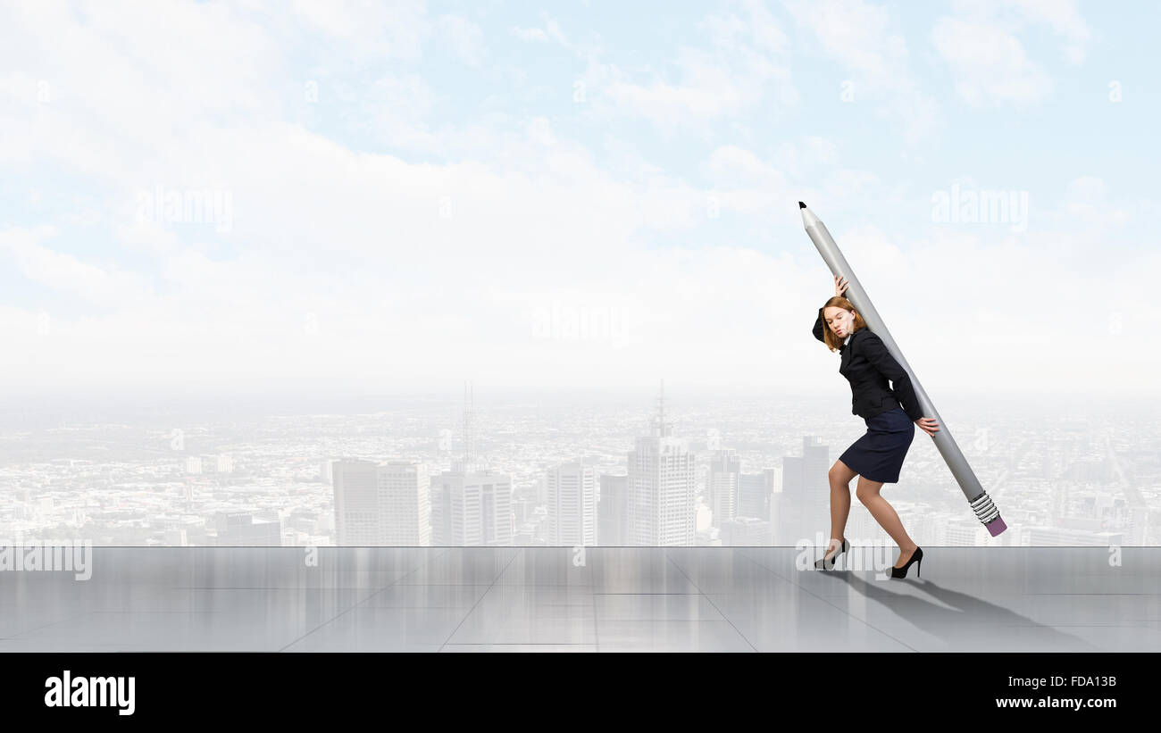 Young businesswoman carrying big pencil on back Stock Photo - Alamy