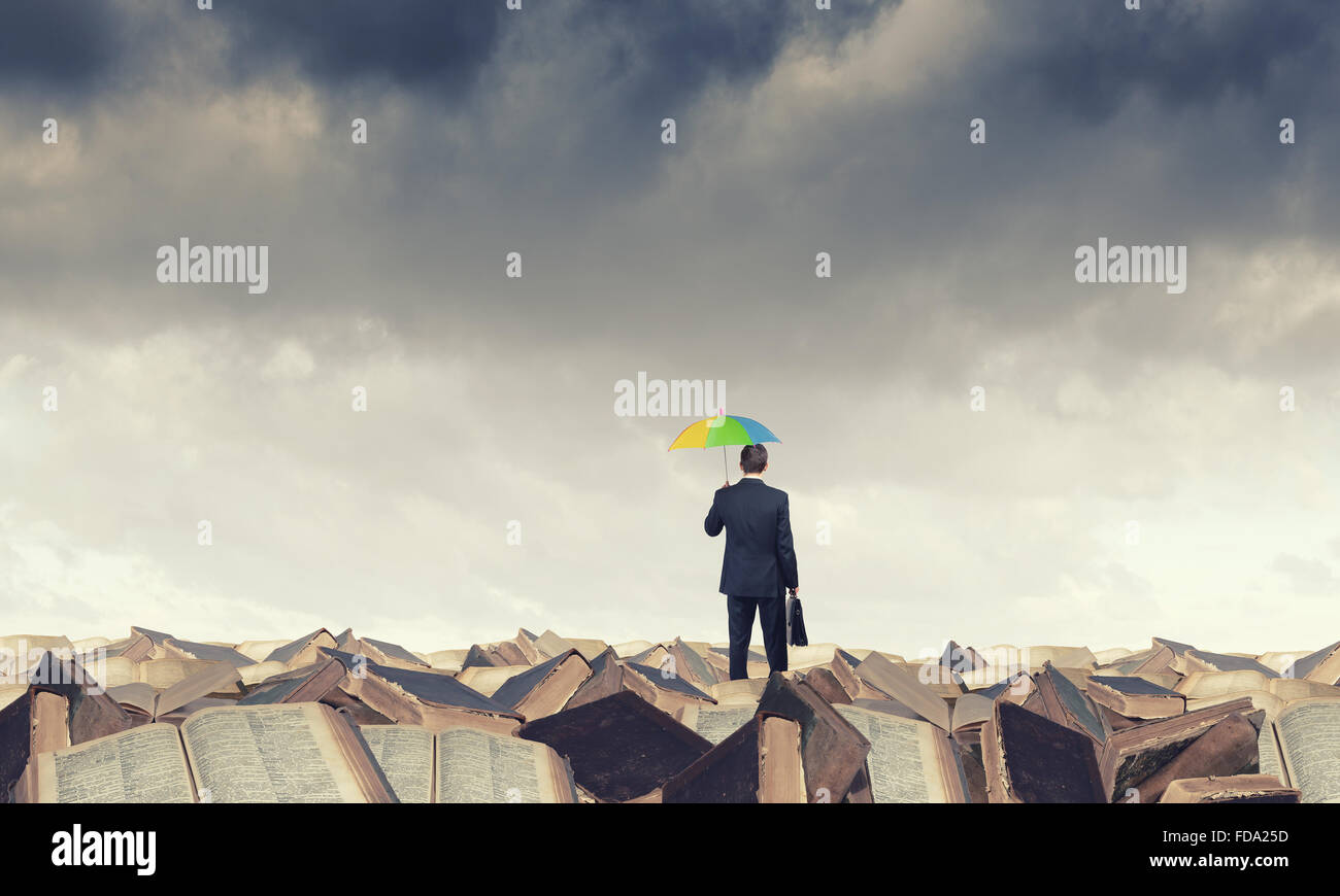 Businessman standing with back on pile of old books with colorful ...