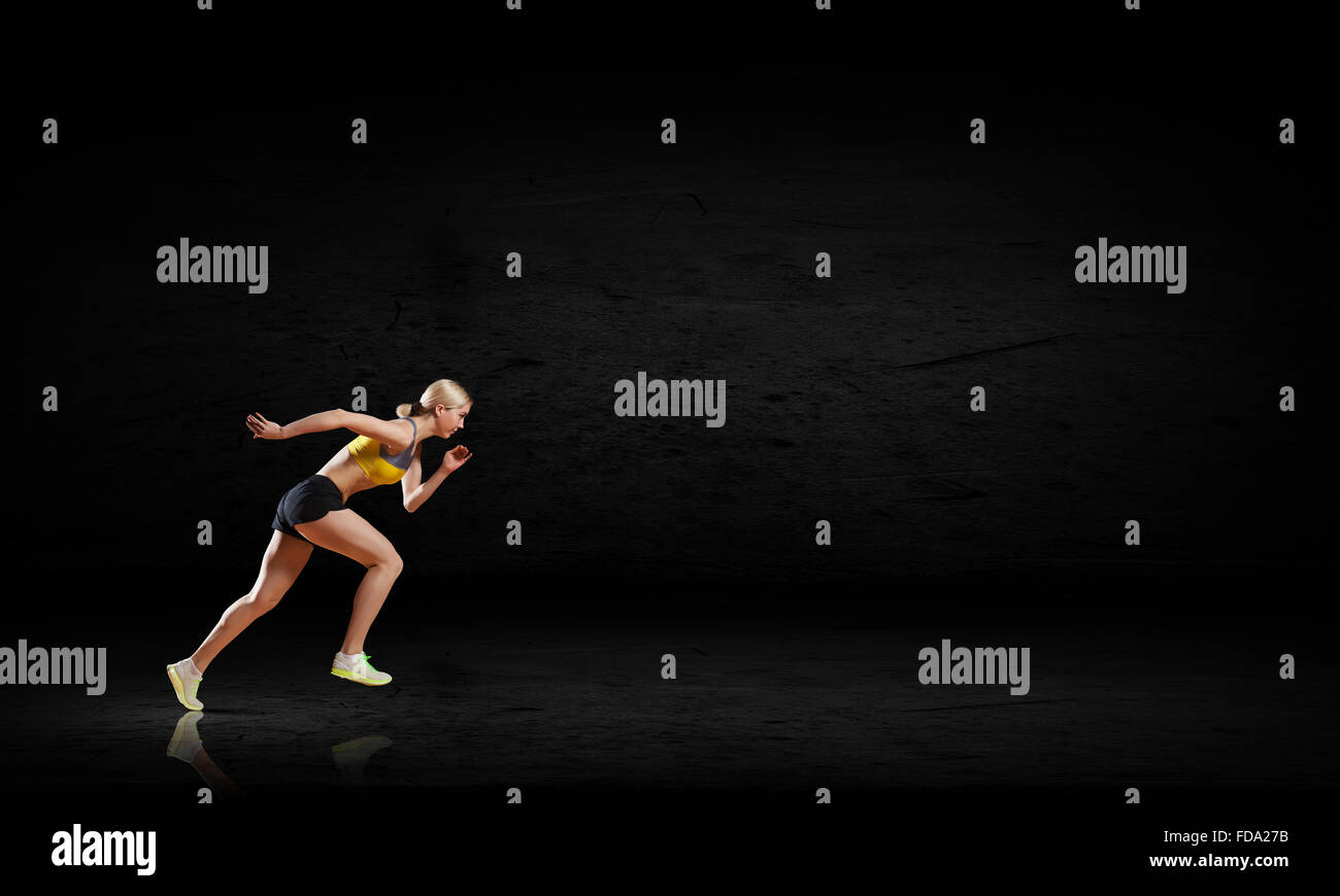 Young woman athlete running fast on dark background Stock Photo - Alamy