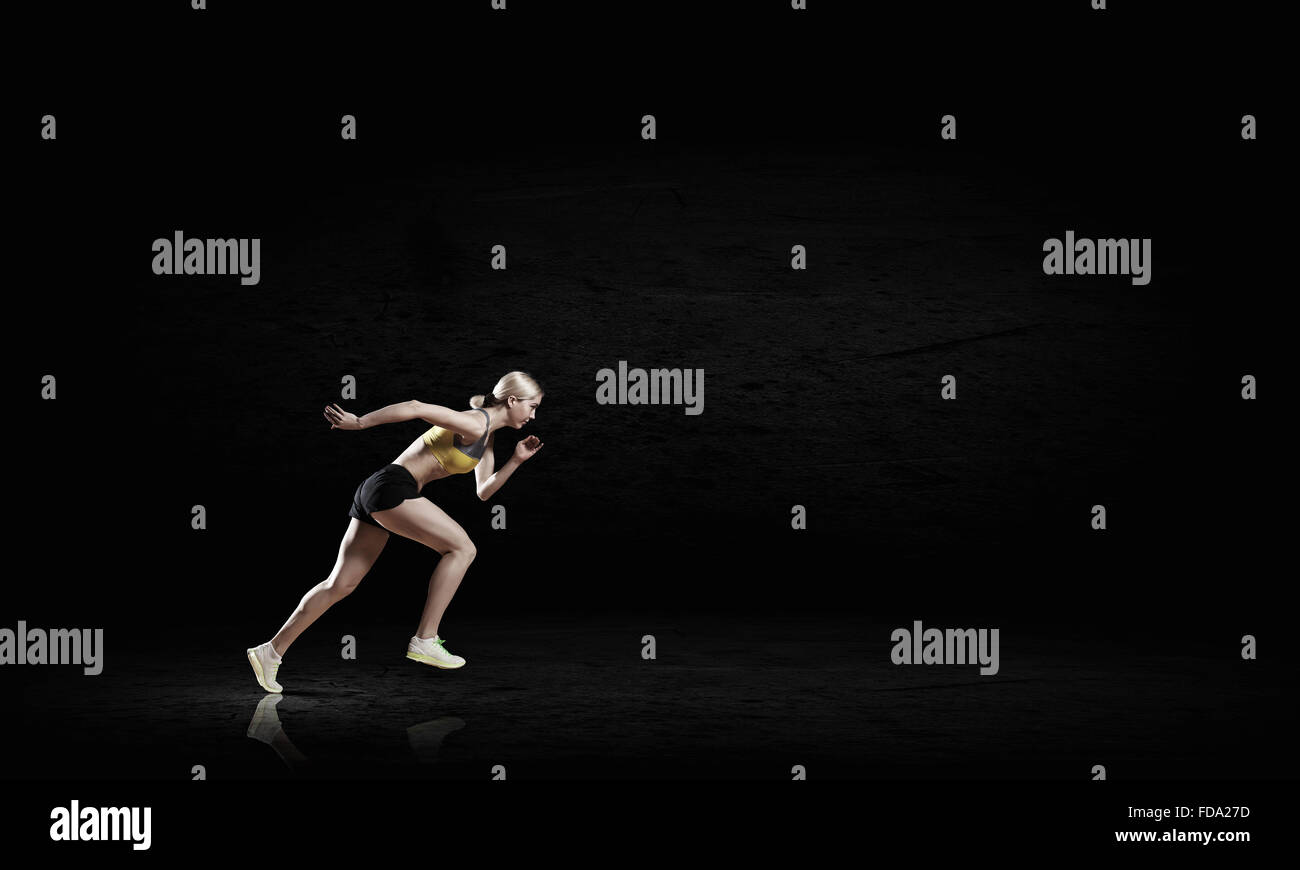 Young woman athlete running fast on dark background Stock Photo - Alamy