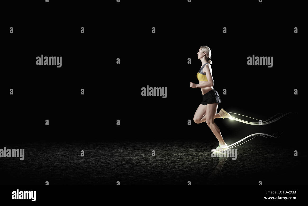 Young woman athlete running fast on dark background Stock Photo - Alamy
