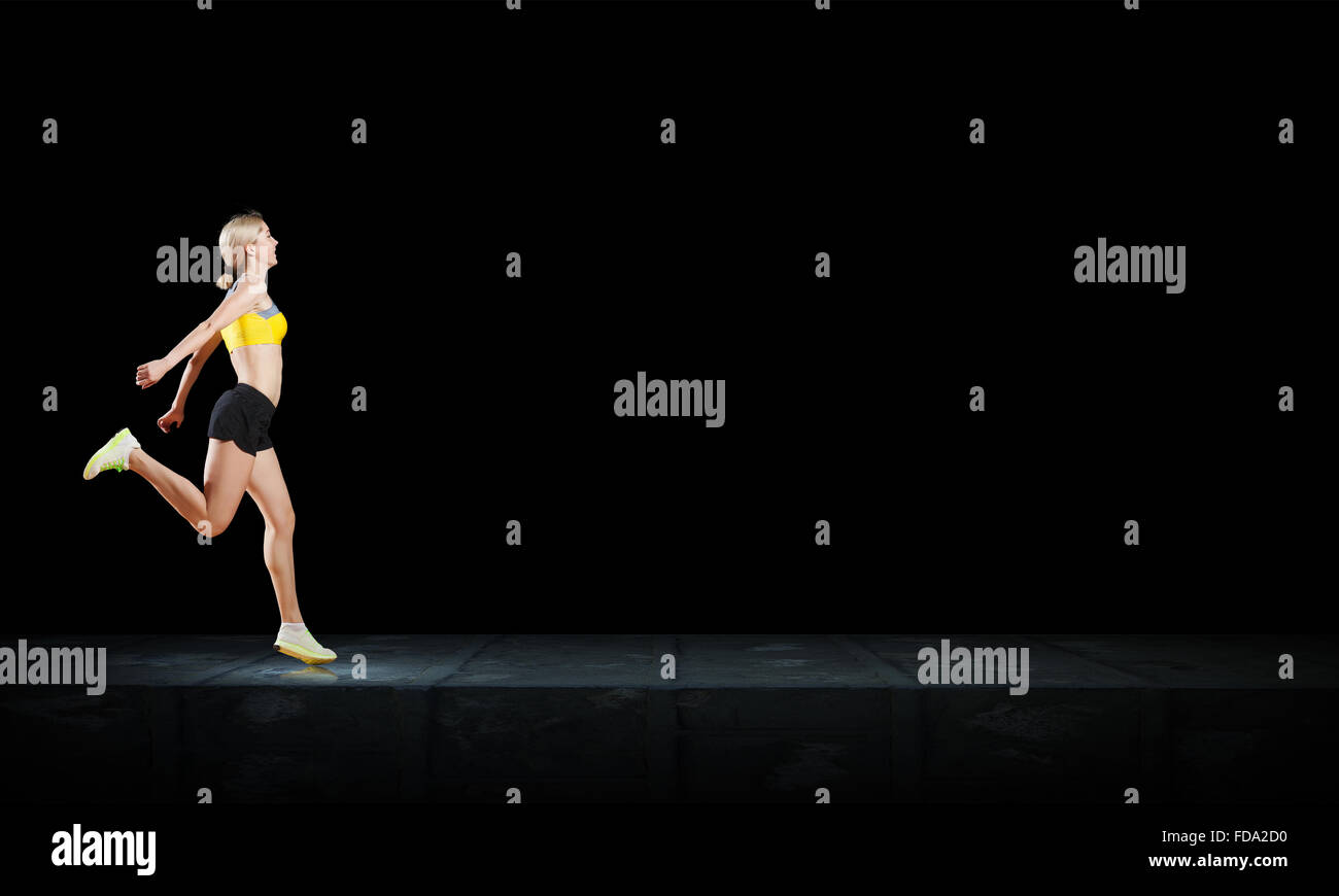 Young woman athlete running fast on dark background Stock Photo - Alamy