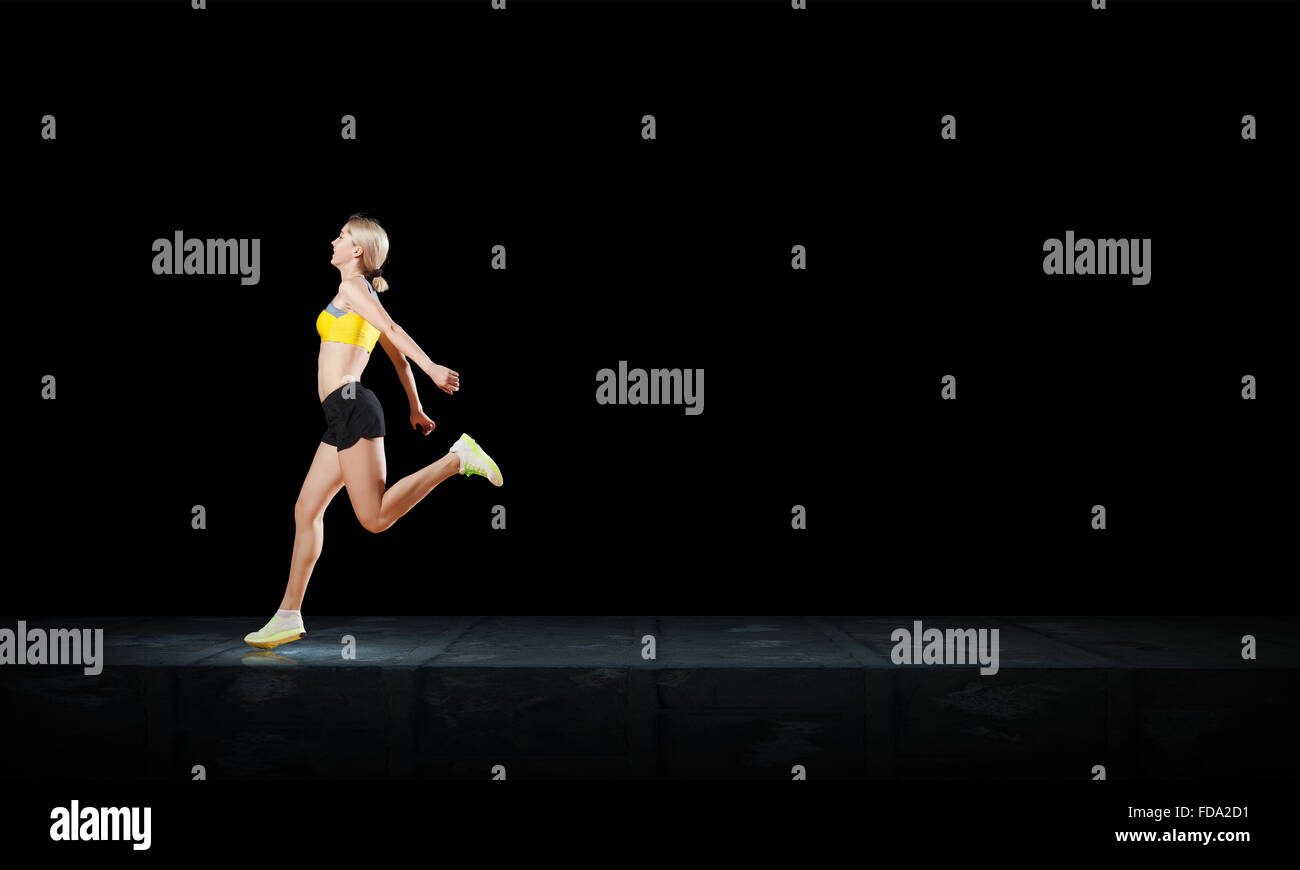 Young woman athlete running fast on dark background Stock Photo - Alamy